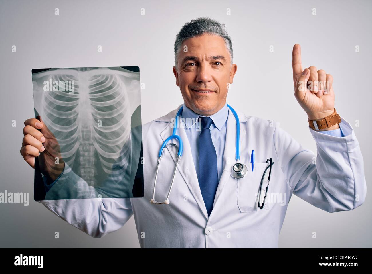 Middle age handsome grey-haired doctor man holding chest xray over ...