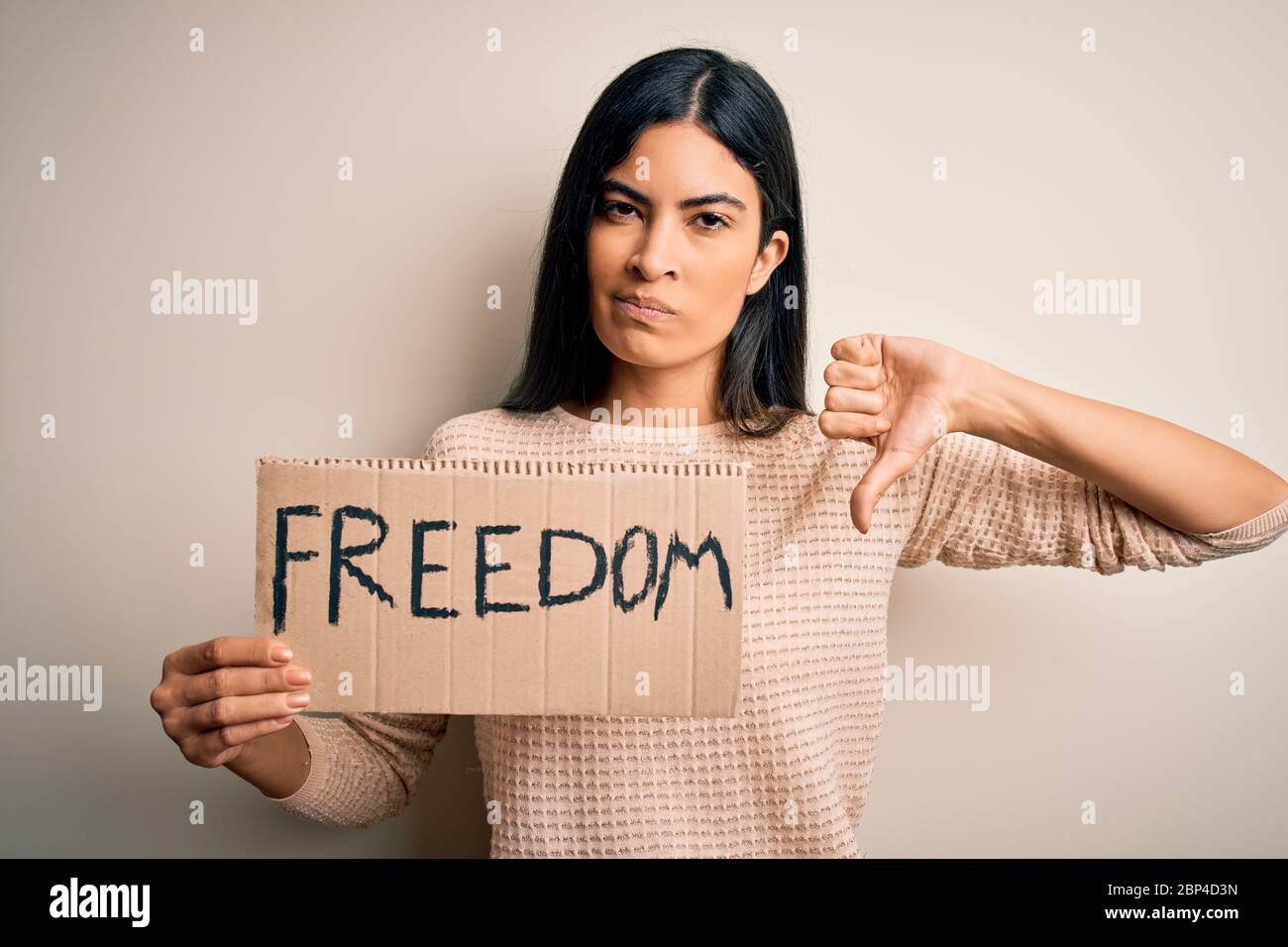 Young beautiful hispanic woman holding protest banner of freedom asking ...