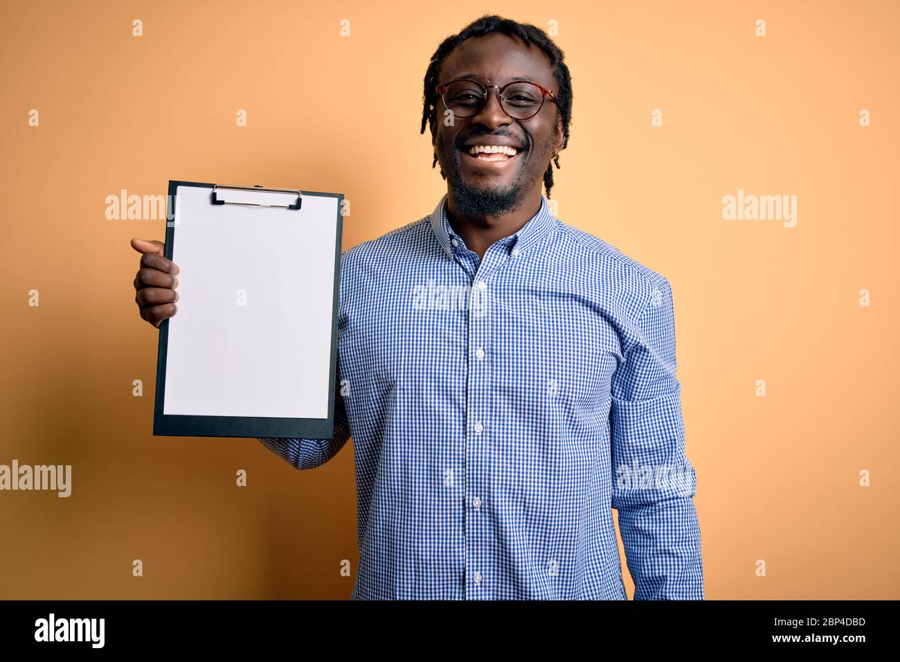 Young african american inspector man wearing glasses holding clipboard ...