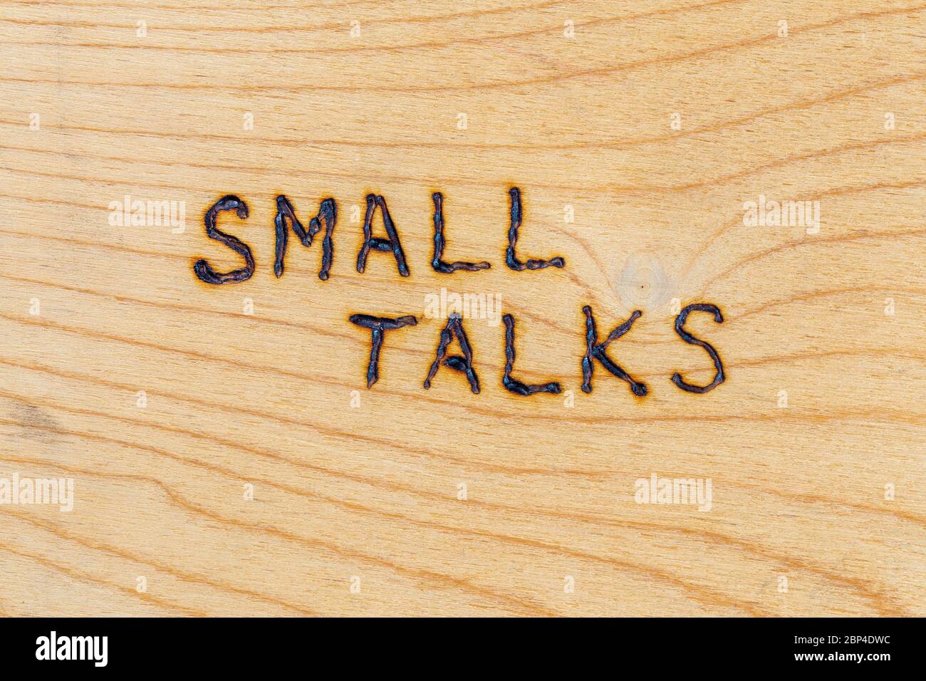 the words small talks handwritten with woodburner on flat plywood ...