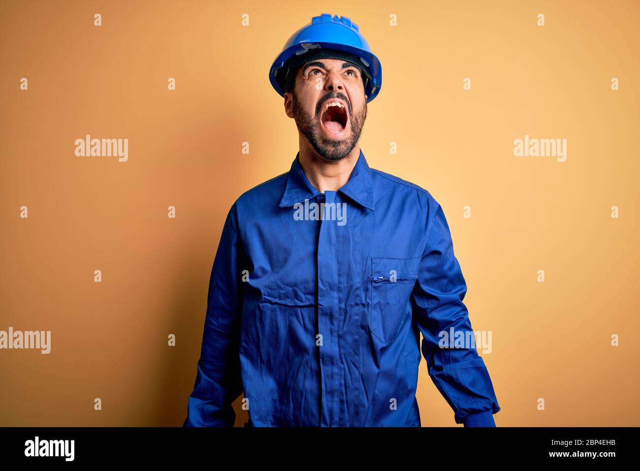 Mechanic man with beard wearing blue uniform and safety helmet over ...