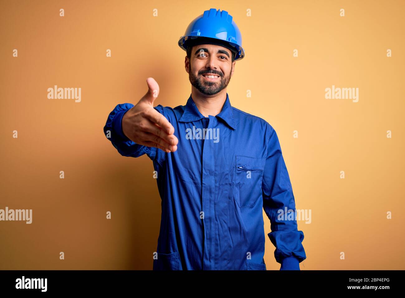 Mechanic man with beard wearing blue uniform and safety helmet over ...