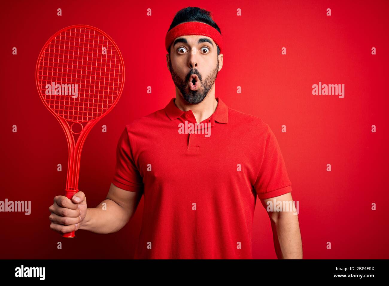 Young handsome sportsman with beard playing tennis using racket over ...