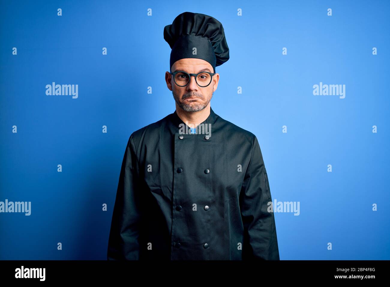 Young handsome chef man wearing cooker uniform and hat over isolated ...