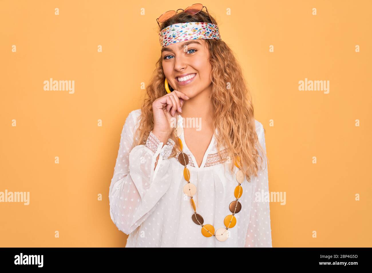 Young beautiful blonde hippie woman with blue eyes wearing sunglasses ...