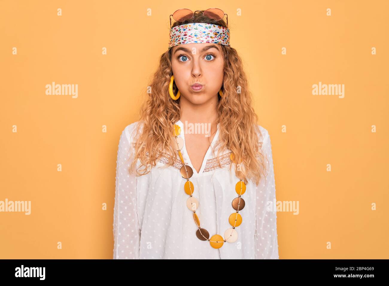 Young beautiful blonde hippie woman with blue eyes wearing sunglasses ...