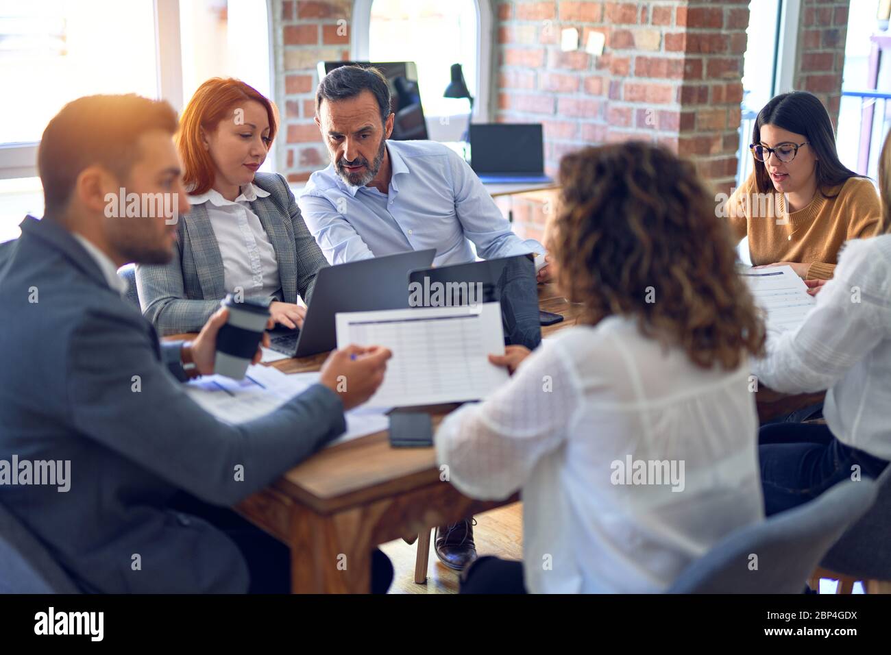 Group of business workers working together. Sitting on desk using ...