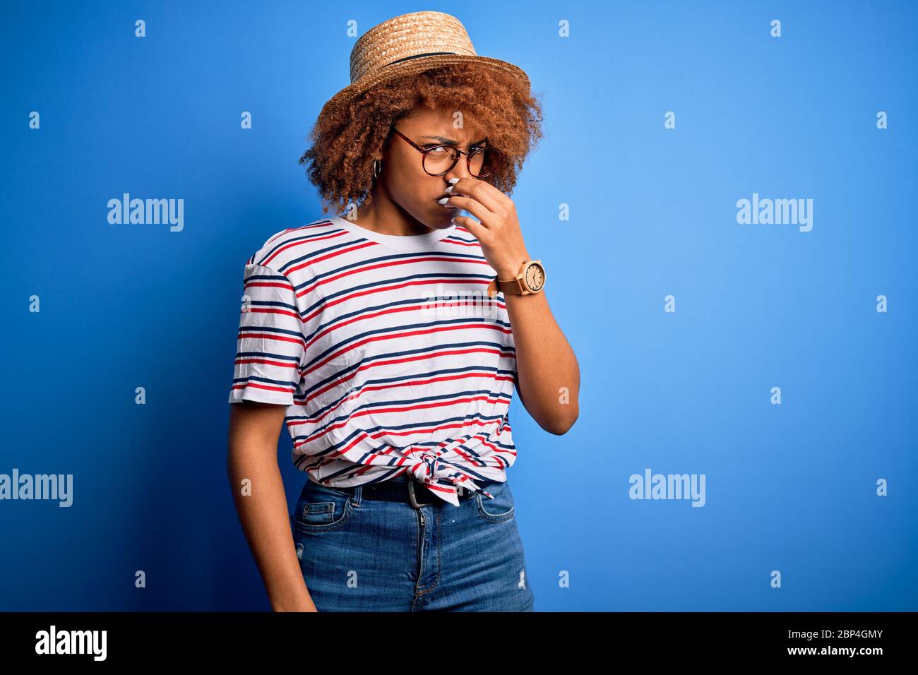 African American woman with curly hair on vacation wearing summer hat ...