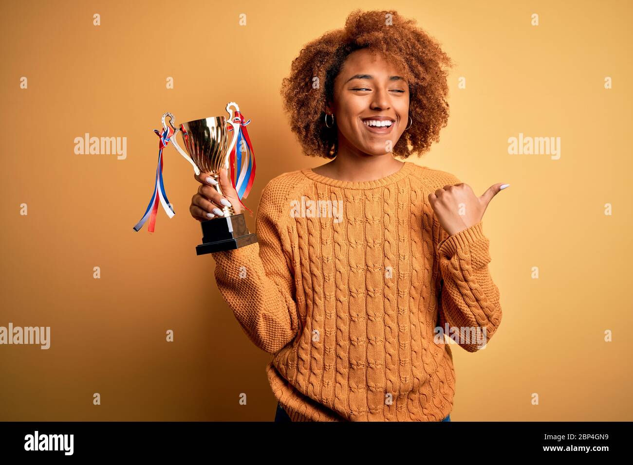 Young African American afro woman with curly hair holding winner ...