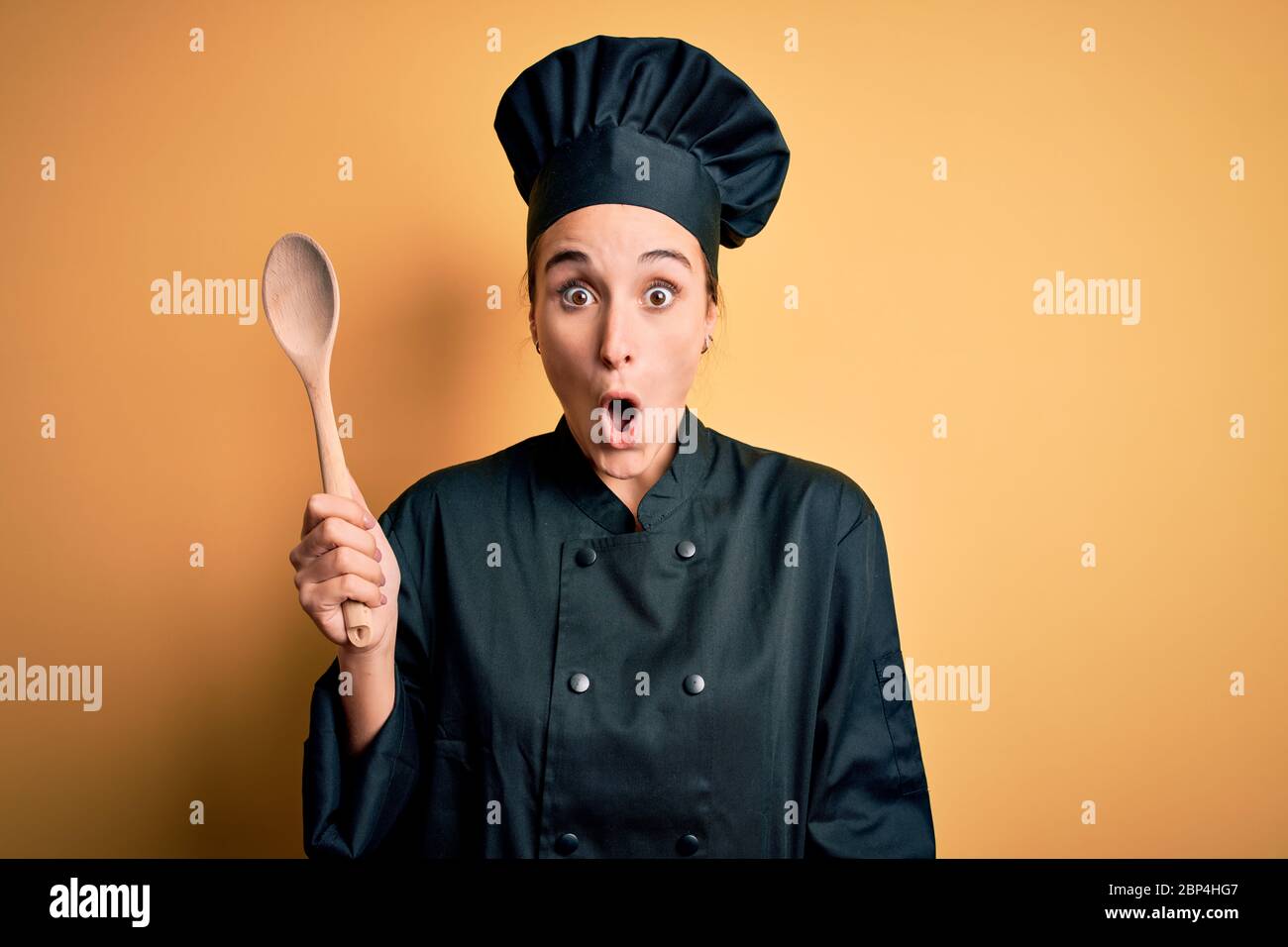 Young beautiful chef woman wearing cooker uniform and hat holding ...