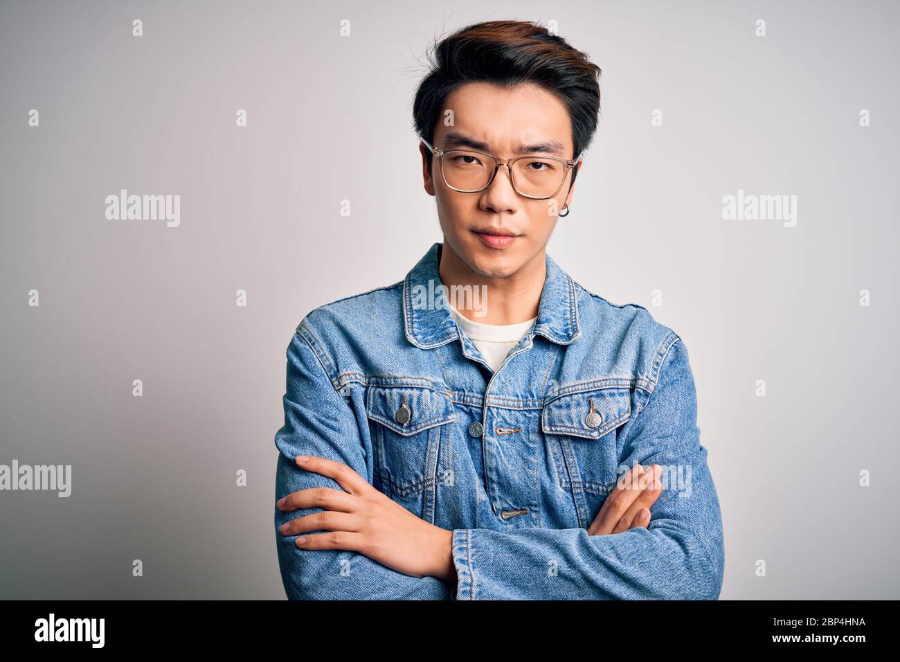 Young handsome chinese man wearing denim jacket and glasses over white ...