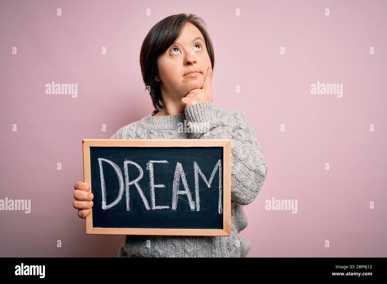 Young down syndrome woman holding blackboard with dream word as message ...