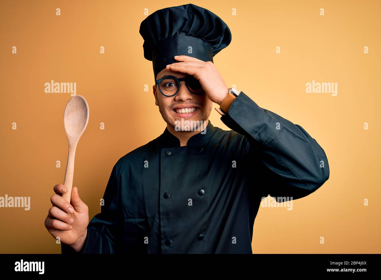 Young brazilian chef man wearing cooker uniform and hat holding wooden ...