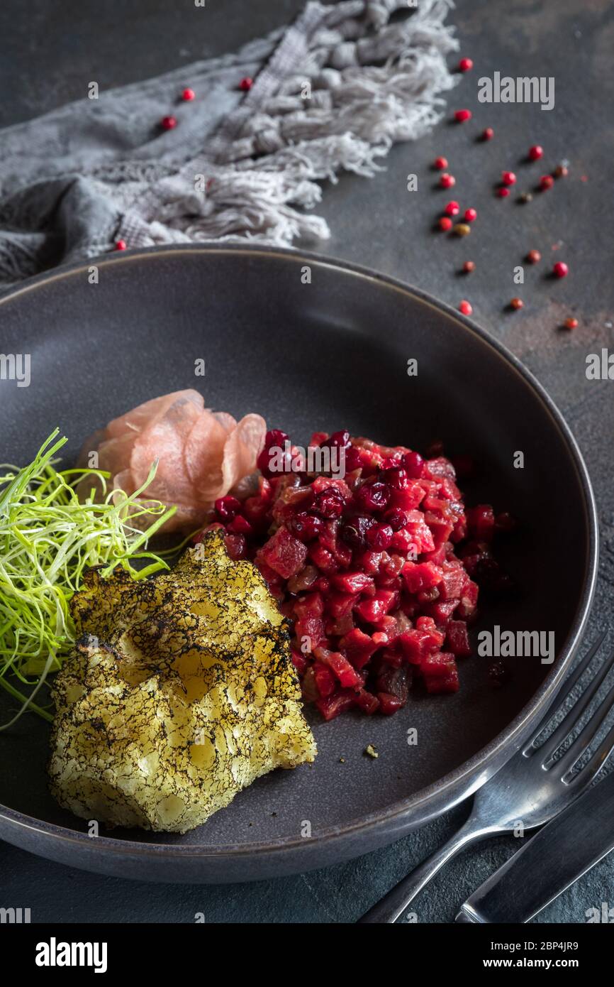Beef tar-tar with dried cranberries and daikon on gray background ...