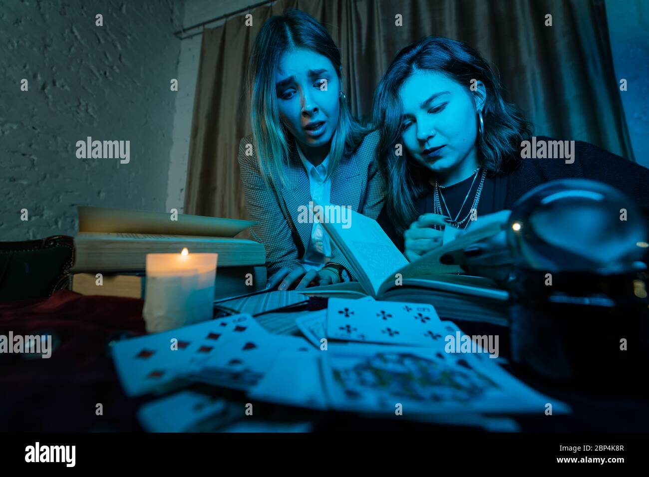 Two women are reading a mysterious book Stock Photo - Alamy