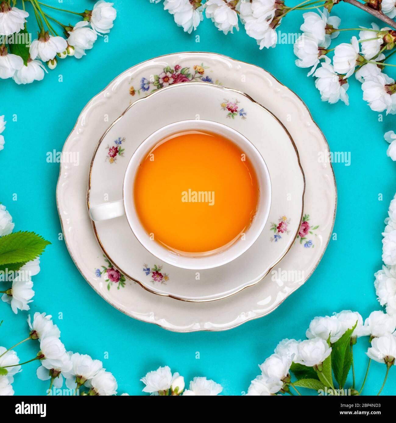 Traditional tea cup and saucer on a pastel blue background. Golden tea ...