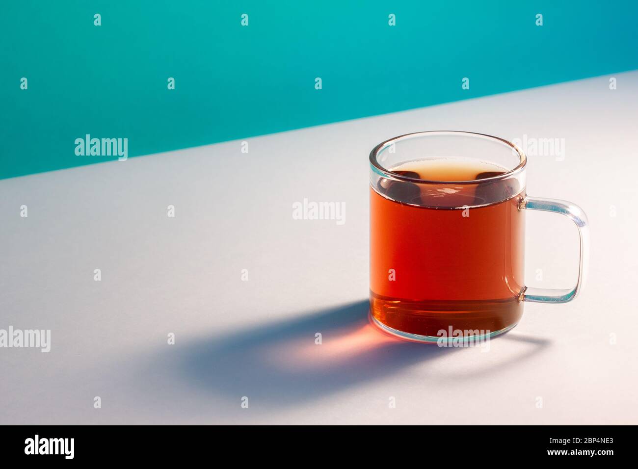 A glass cup of tea on a table with a pastel blue background. Bright ...