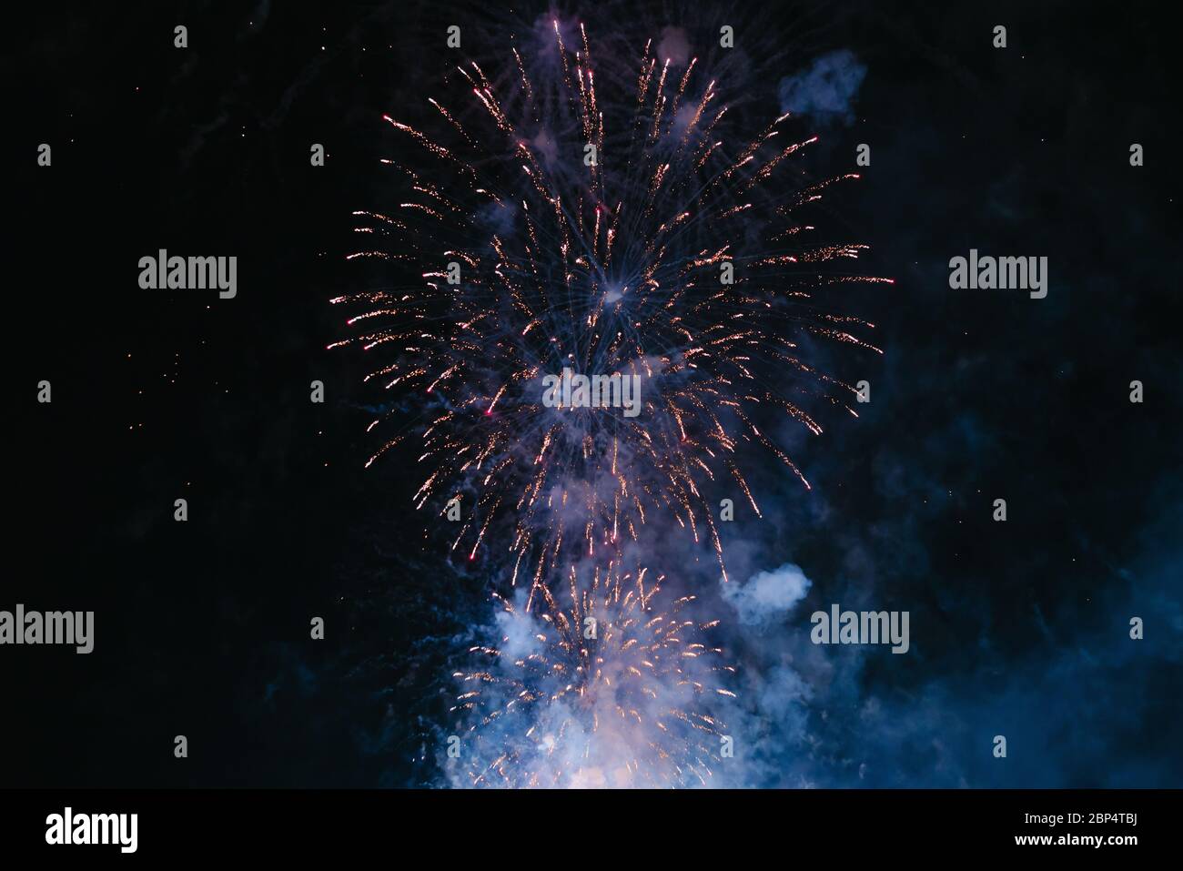 Blue and yellow fireworks with smoke over the black sky. Low key ...