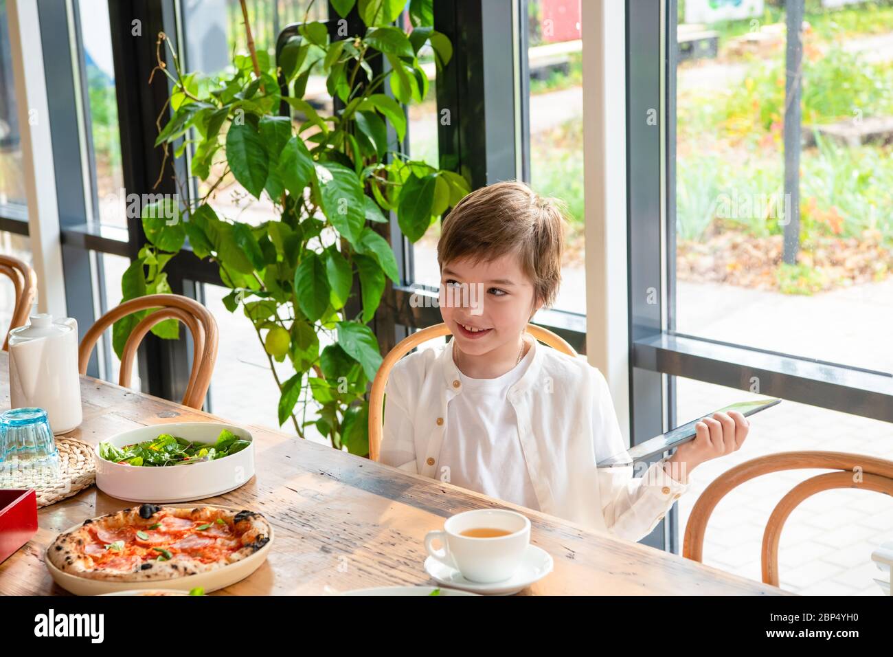 A kid at dinner table with a tablet Stock Photo - Alamy