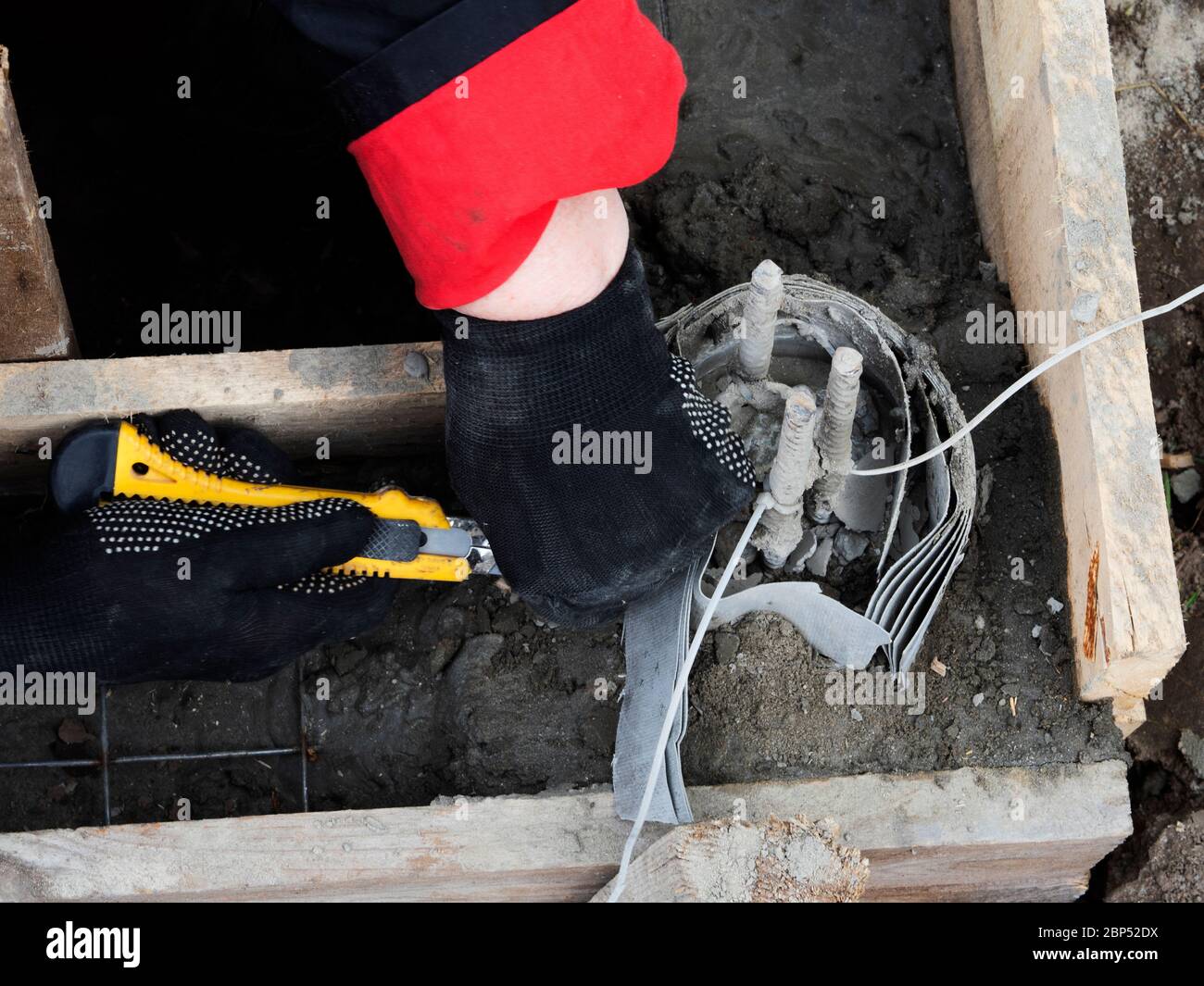 Gloved hands of a worker cutting a soft formwork from columns in a ...