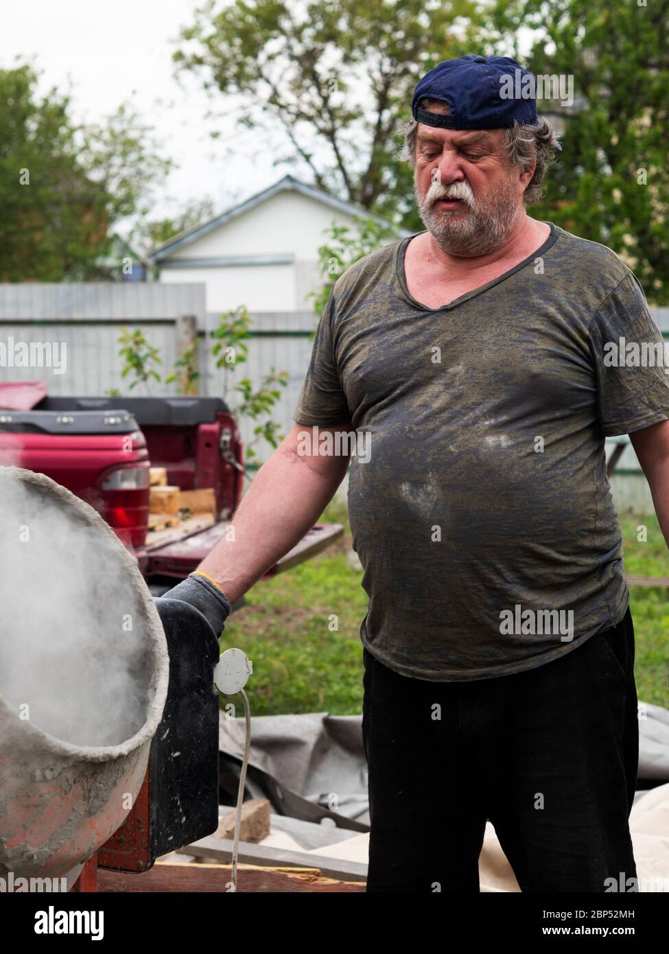 Mature Caucasian man mixes cement mortar in concrete mixer Stock Photo ...