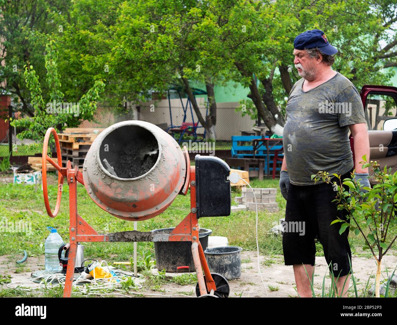 Mature Caucasian man mixes cement mortar in concrete mixer Stock Photo ...