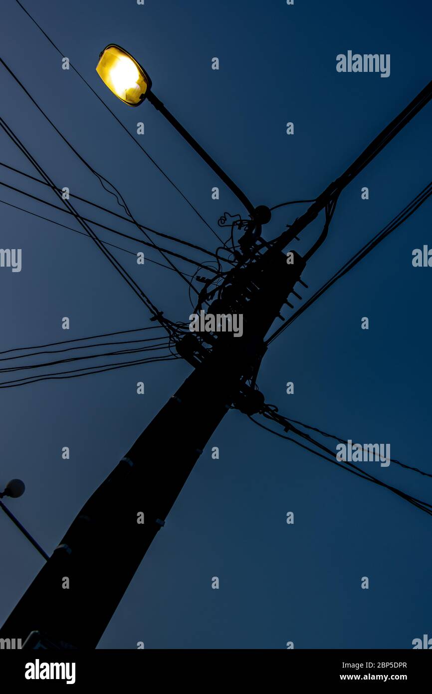 Street lamp shining against dark blue sky. Pole of power lines with ...
