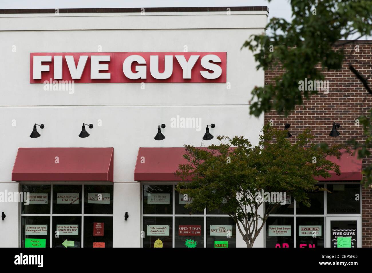 A logo sign outside of a Five Guys restaurant location in Richmond ...