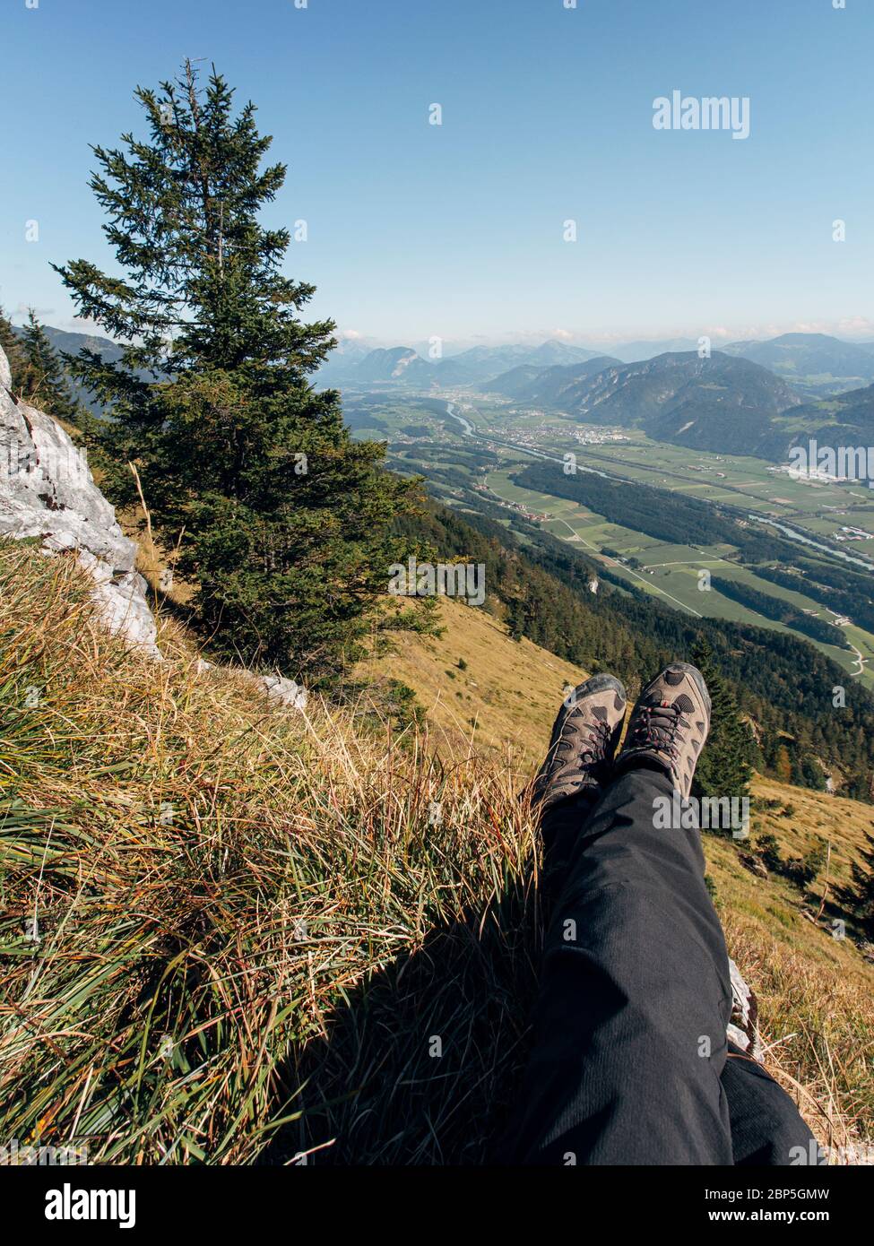Legs of a male hiker hanging over the edge of a mountain over the ...