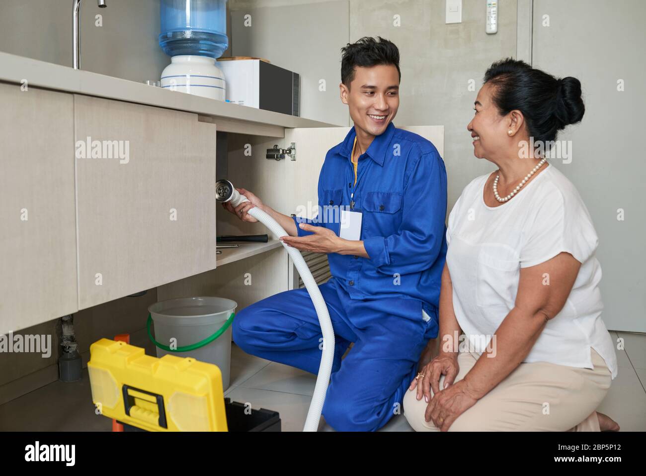 Smiling plumber explaining senior apartment owner how he is going to ...