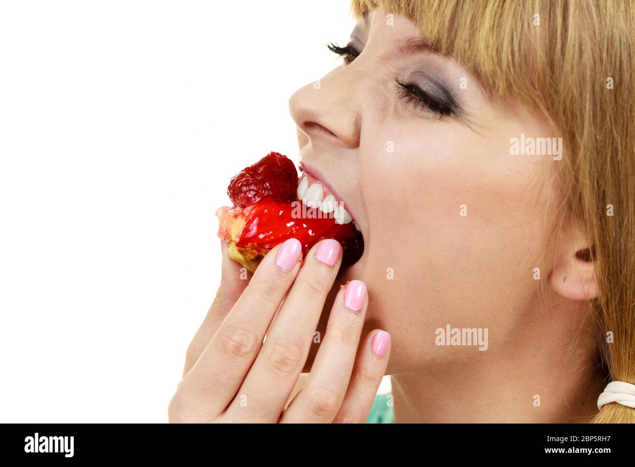 Woman holds cake cupcake in hand taking a huge bite out of dessert ...