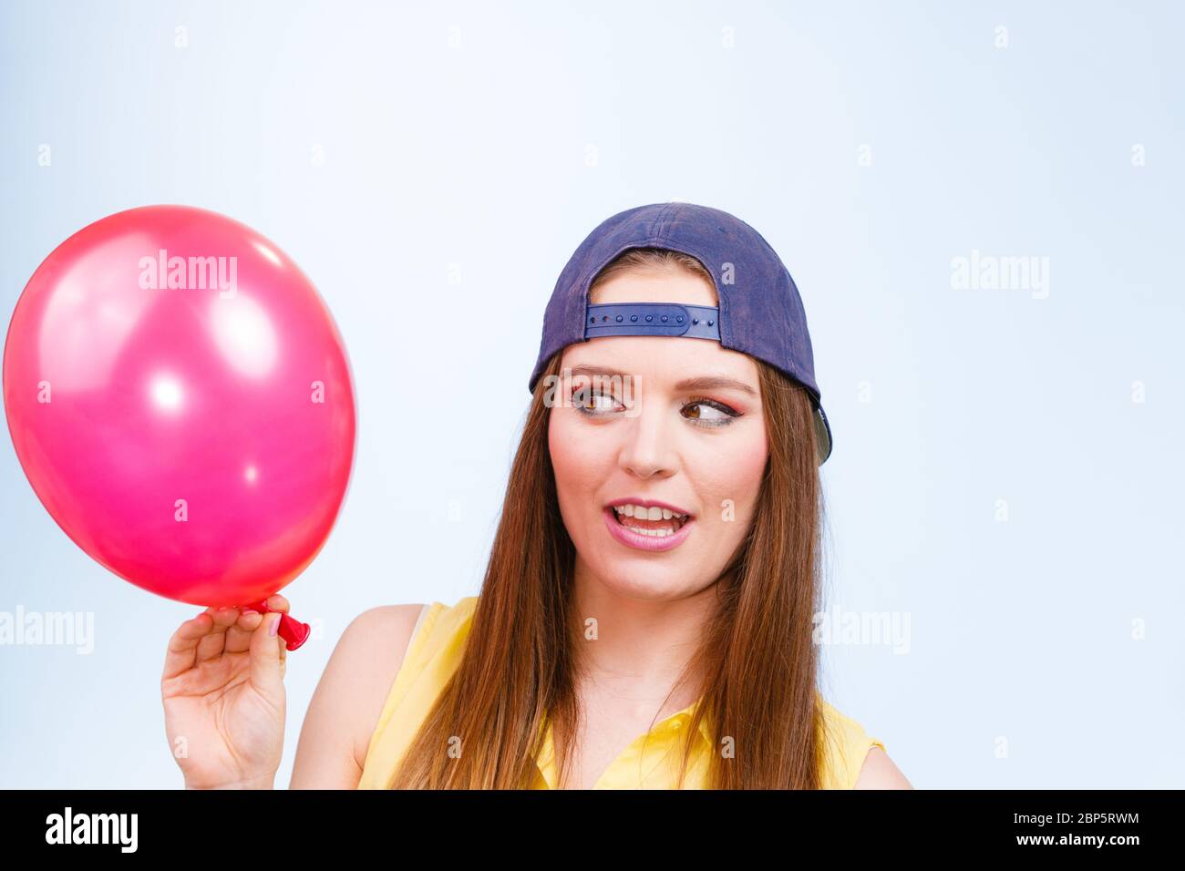 Teenage girl making funny silly faces. Young trendy woman in jeans cap ...