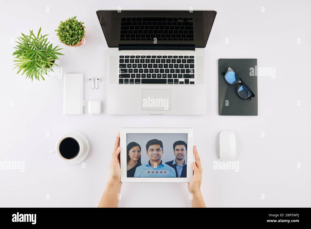Businesswoman sitting at office desk and video calling her team via ...