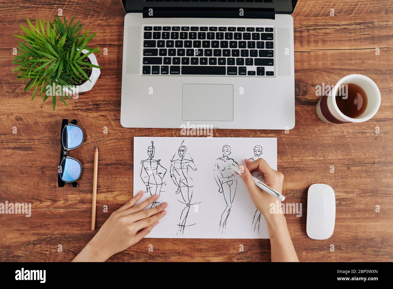 Hands of fashion designer drawing sketches when working at wooden ...