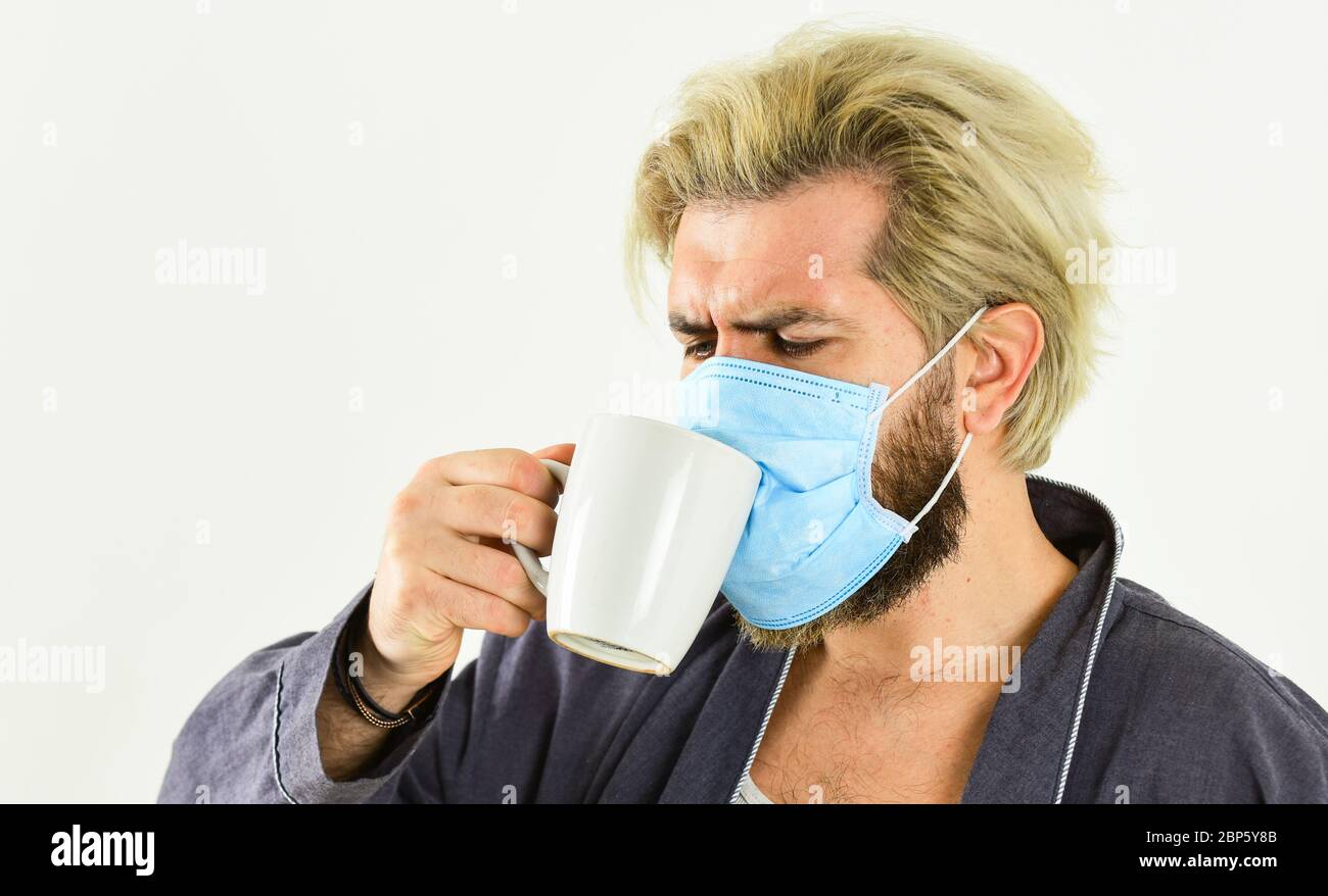 medical mask as corona protection. man drink coffee in respirator ...
