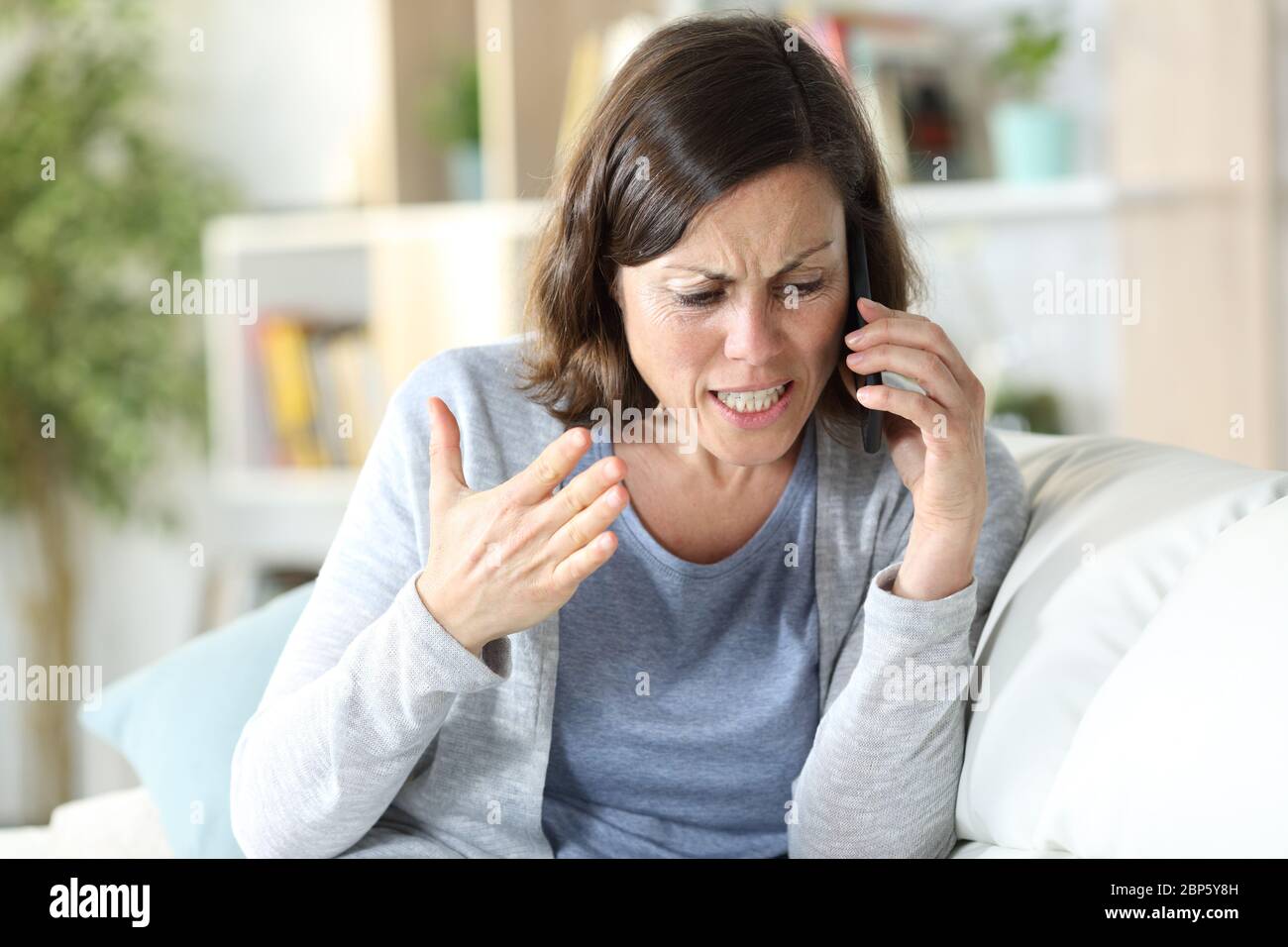 Angry middle age woman arguing calling on smart phone sitting on a ...