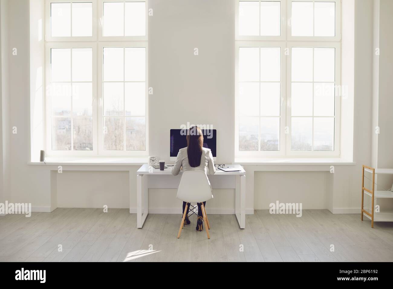 White bright spacious office. Back view of a female employee working at ...