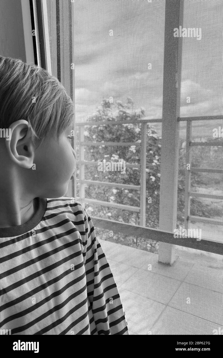 the boy stays at home and looks out the window. boy misses his friends ...
