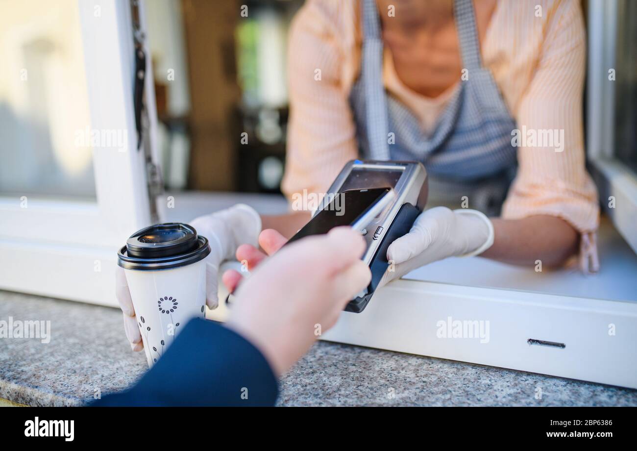 Woman serving coffee through window, contactless payment and back to ...