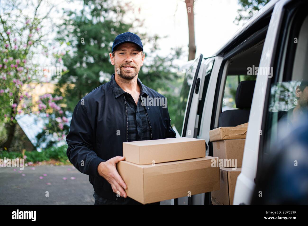 Front view of delivery man courier delivering parcel box in town Stock ...