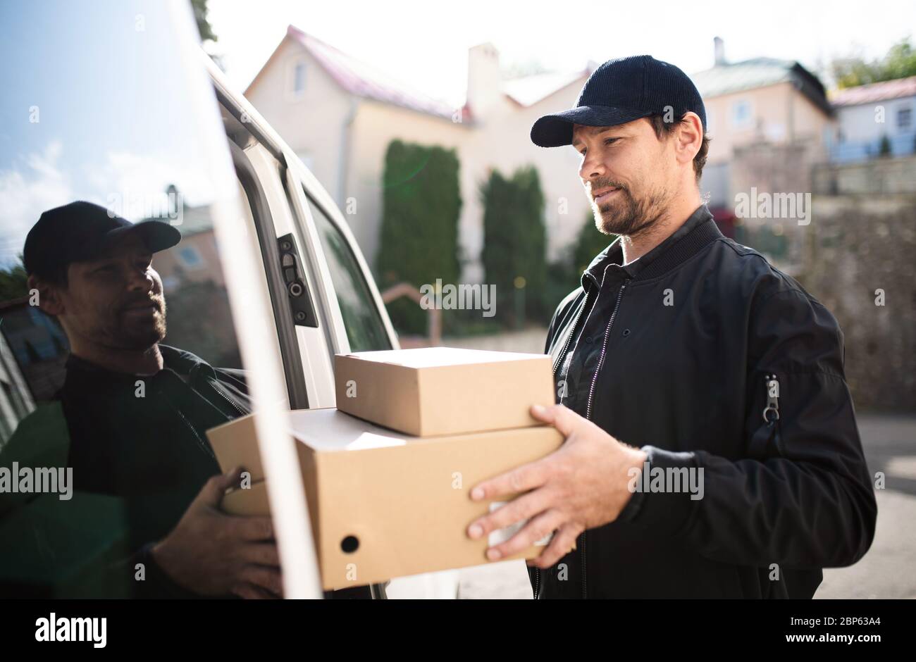 Side view of delivery man courier delivering parcel box in town Stock ...