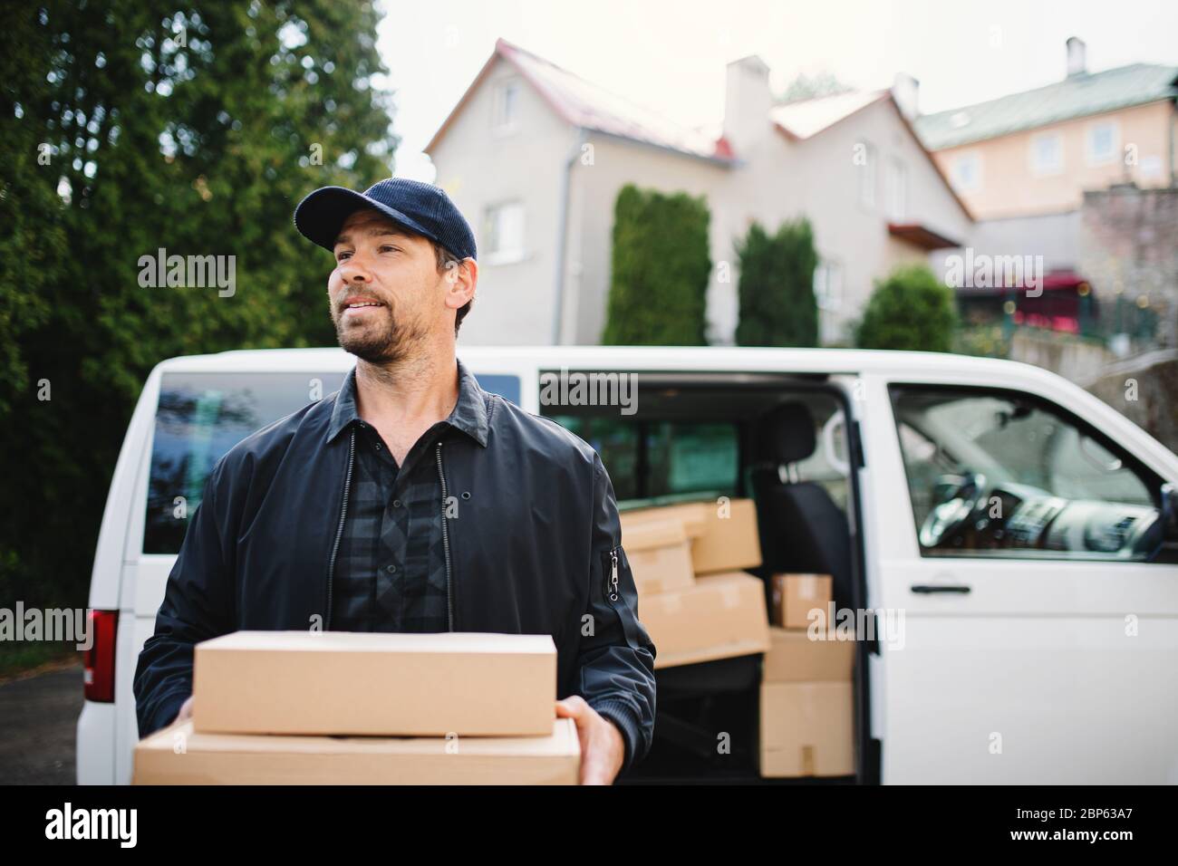 Front view of delivery man courier delivering parcel box in town Stock ...