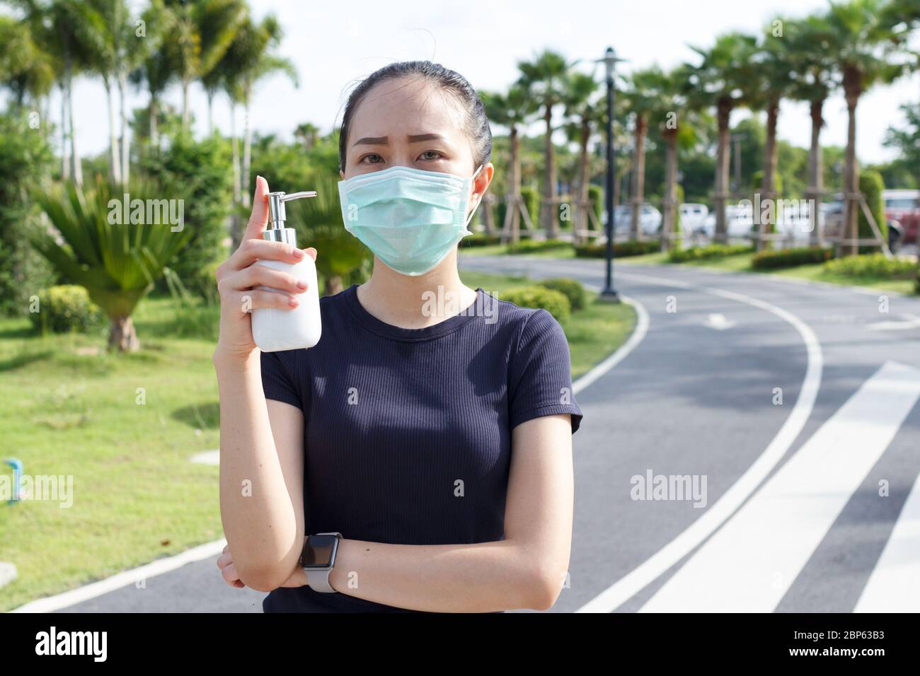 Young woman in medical protective mask and holding an alcohol in hand ...