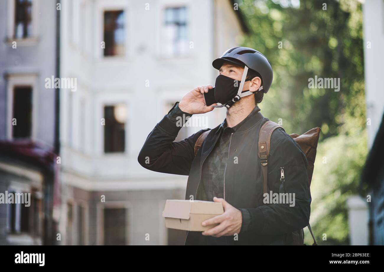Delivery man courier with face mask and bicycle using smartphone in ...