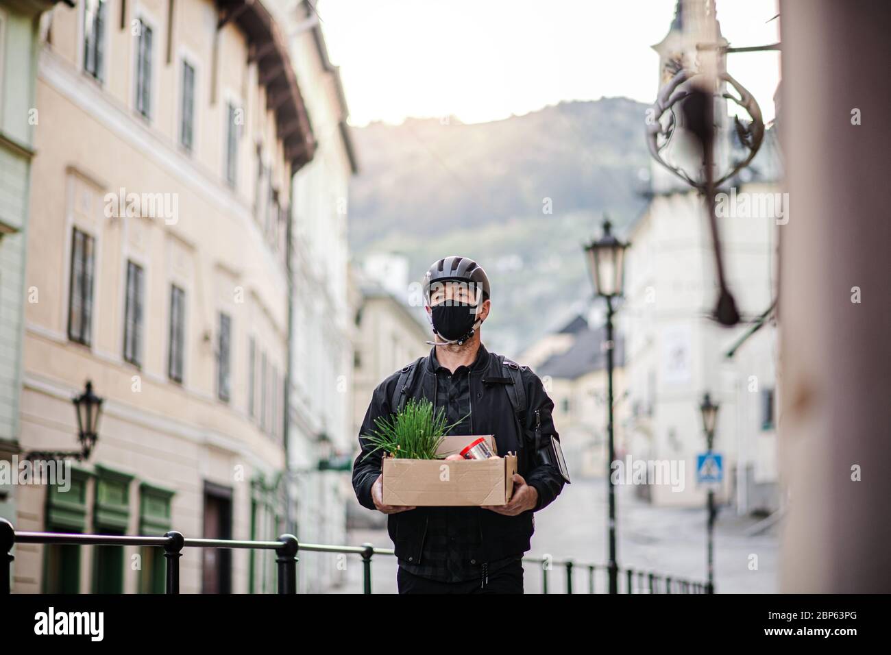 Delivery man courier with face mask delivering groceries in town Stock ...