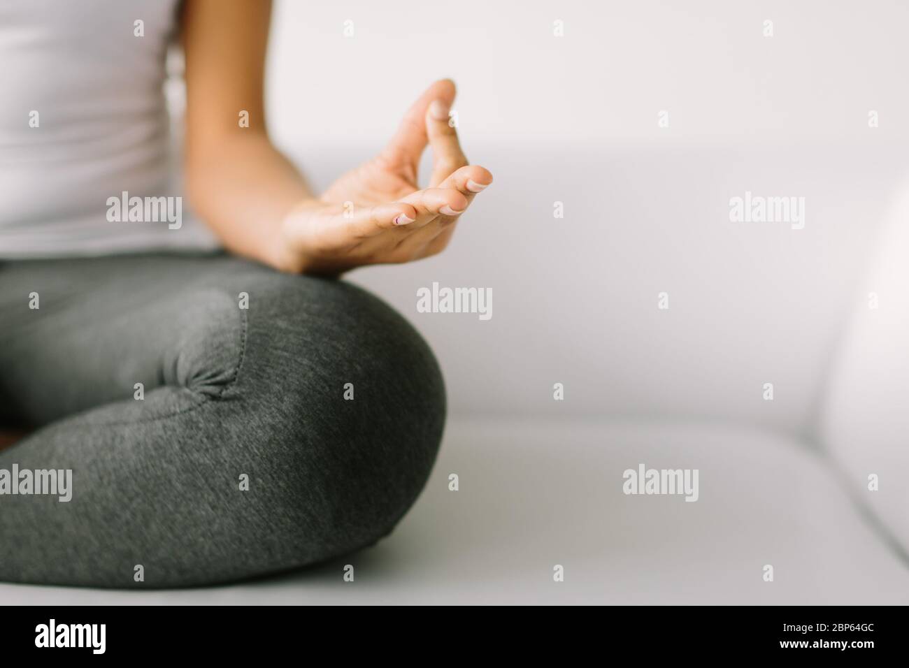 An African American young women sitting in the lotus position on white ...