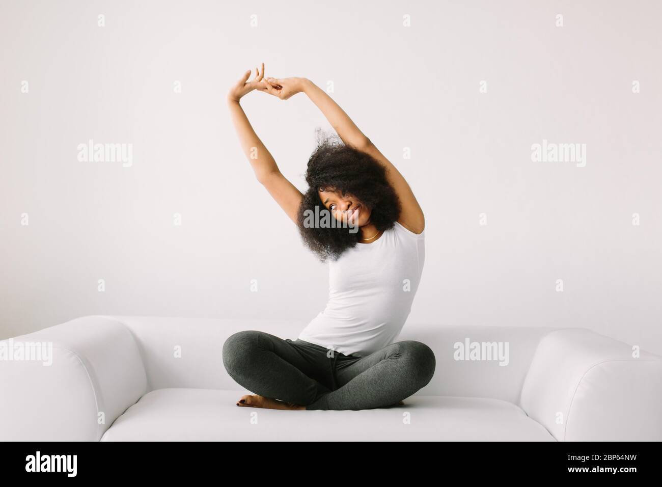 An African American young women sitting in the lotus position on white ...