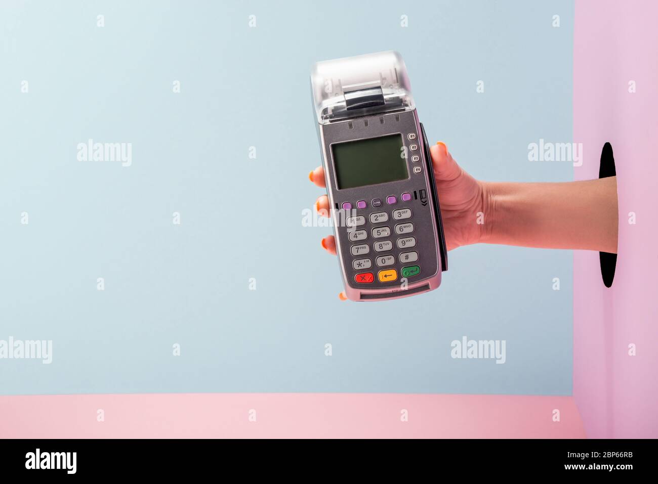 Hand holding a POS terminal with printed receipt on blue and pink ...