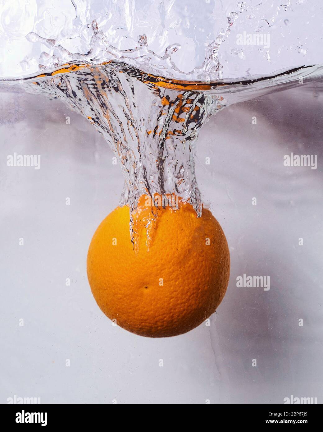 Orange falling into the water and creating splashes Stock Photo - Alamy
