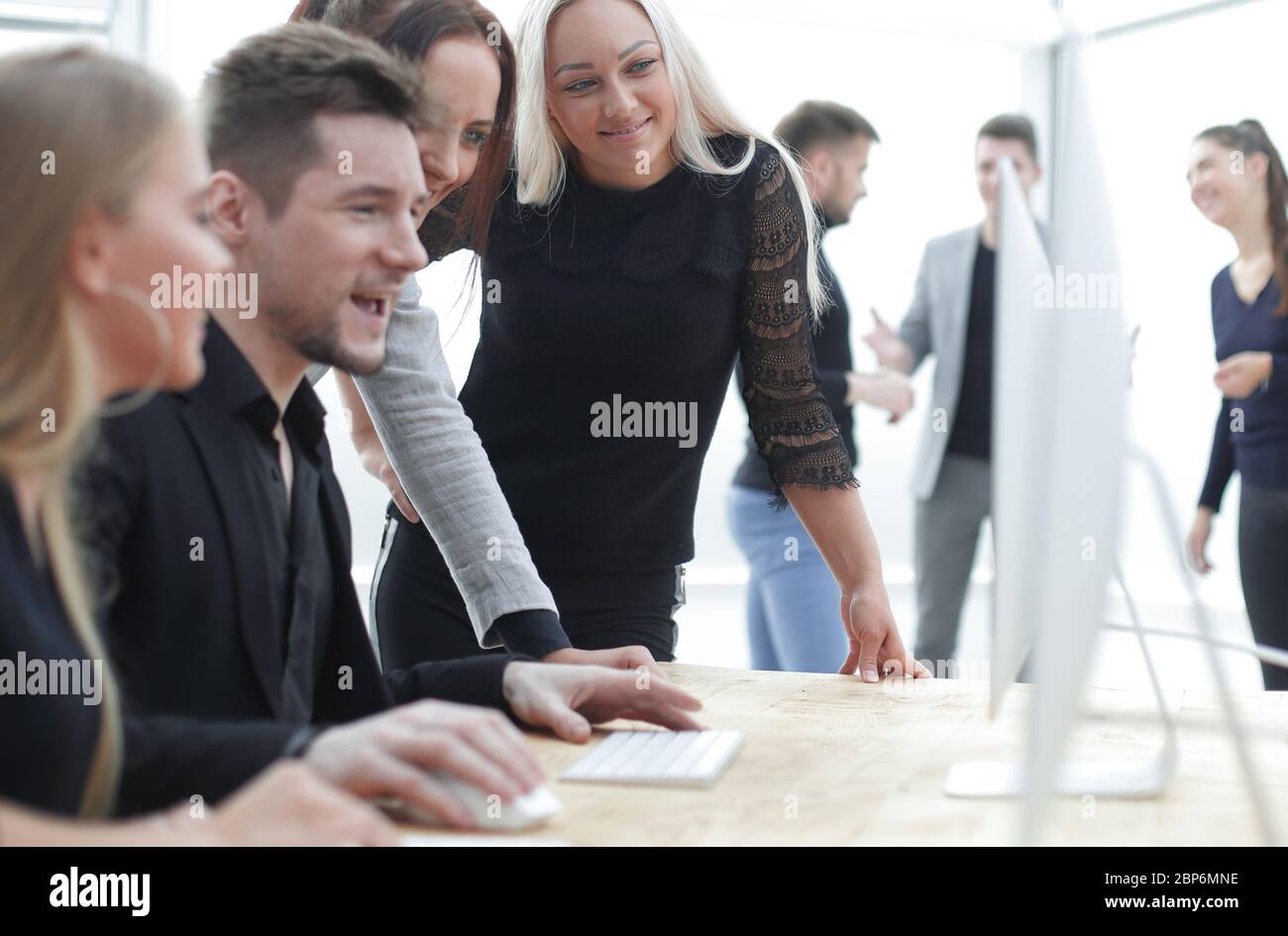 group of young employees looking at the screens of office computers ...